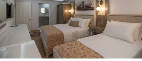 Quarto de hotel com duas camas, uma escrivaninha e uma pequena cozinha.