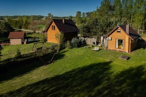 Uma propriedade rural com duas casas de madeira, um quintal cercado e um lago.
