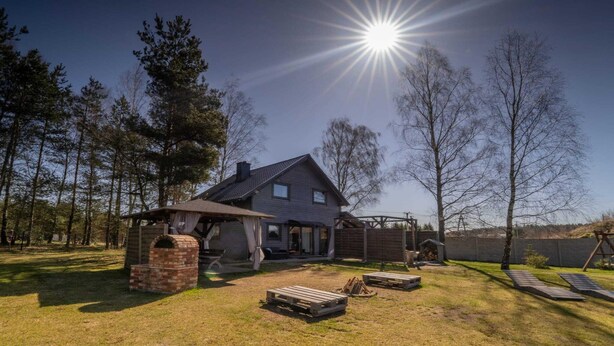 Uma casa com chaminé, espaço para churrasco e um deck de madeira.