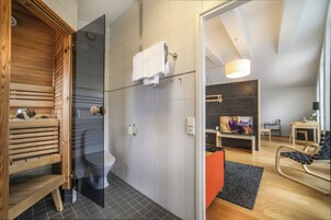 Uma casa de banho moderna com sauna de madeira, sanita e chuveiro.