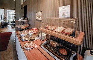 Um buffet com diversos pratos, um quadro na parede e um letreiro com itens do menu.