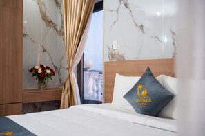 Quarto de hotel com uma cama, mesa de cabeceira, um vaso com flores e vista para o exterior.