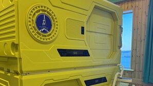 Uma cama beliche amarela com mostrador digital e um emblema circular.