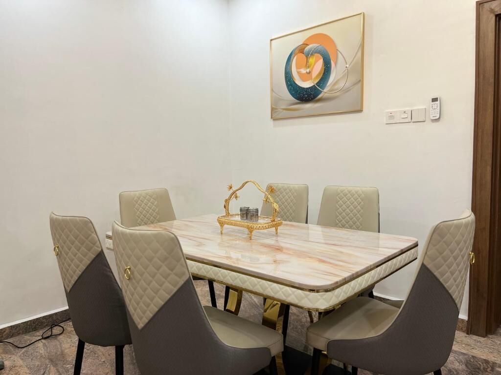 Uma sala de conferência com uma mesa de mármore, seis cadeiras e um objeto decorativo central.