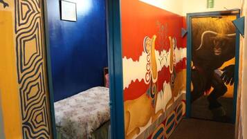 Um quarto com uma cama, uma parede com um mural e uma porta com ilustração de touro.