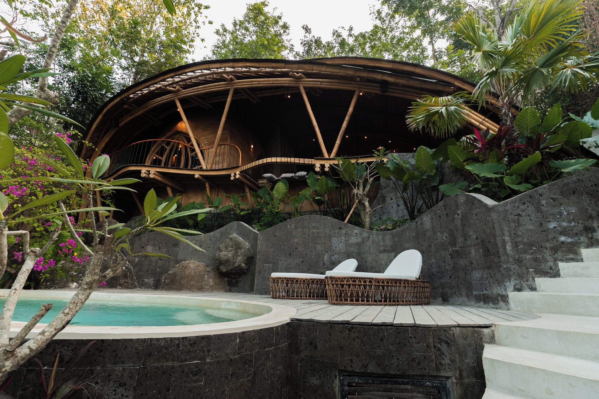 Área de piscina com hidromassagem, espreguiçadeiras e estrutura de bambu.