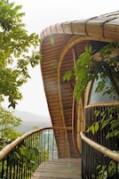 Uma estrutura de madeira com telhado curvo e deck de madeira com guarda-corpos.