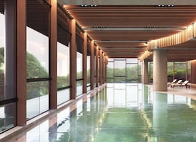 Piscina interior moderna com grandes janelas e vigas de madeira.