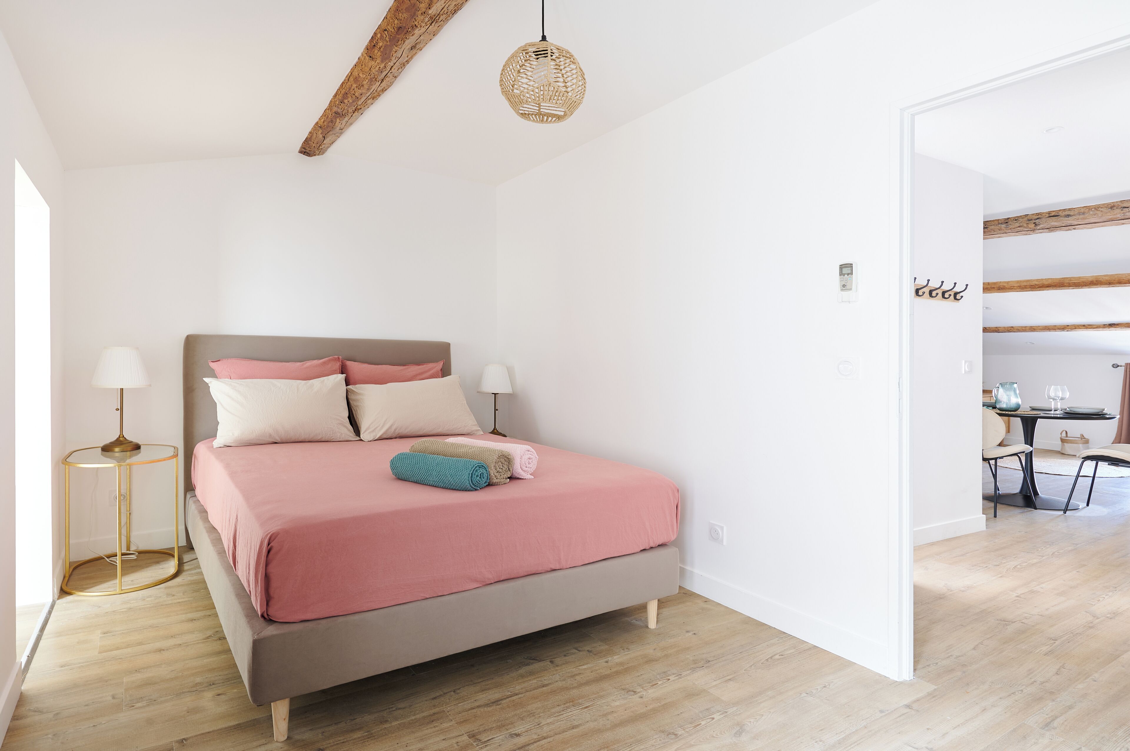 Quarto com cama, luminárias de cabeceira e uma viga de madeira no teto.