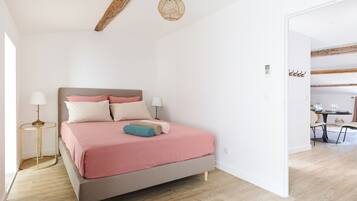 Quarto com cama, luminárias de cabeceira e uma viga de madeira no teto.