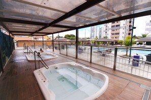 Uma área de piscina no terraço com hidromassagem e espreguiçadeiras.