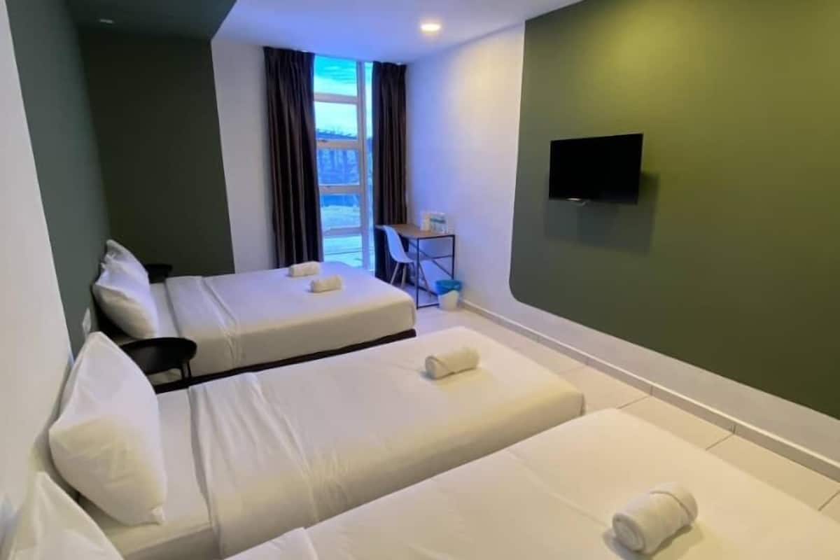 Quarto de hotel com duas camas, uma escrivaninha, uma cadeira, uma televisão e uma janela com cortinas.