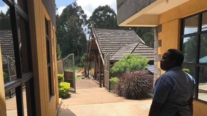 Um corredor com uma porta de madeira, um pequeno jardim e um edifício com telhado de telhas.