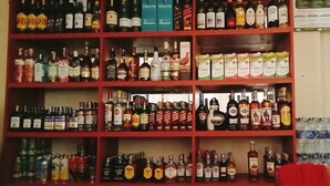 Uma loja de bebidas com várias prateleiras repletas de garrafas e latas diversas.