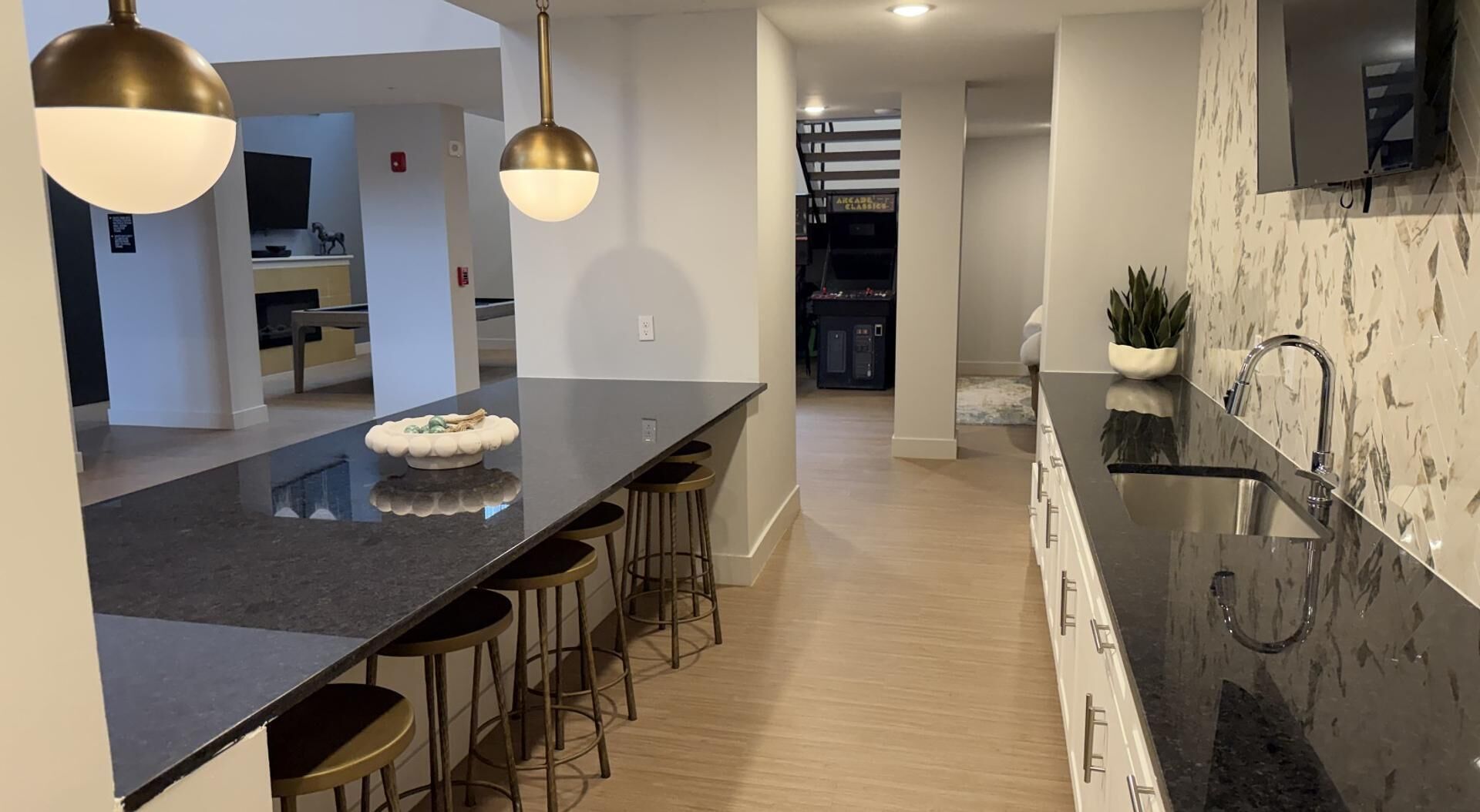 Cozinha moderna com ilha central, banquetas, iluminação pendente e painel de backsplash em mármore.