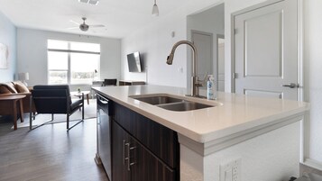 Cozinha moderna com uma ilha grande, armários de madeira escura, pia de aço inoxidável e ventilador de teto.