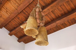 Teto com vigas de madeira e lustre de cesta trançada.