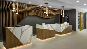 Uma área de recepção com três balcões de mármore, painéis de madeira e um design de parede ondulado.
