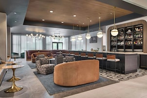 Uma área de bar moderna com assentos, balcão e variedade de bebidas.