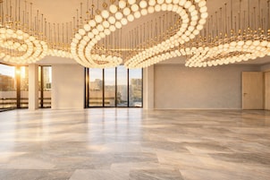 Um hall de hotel espaçoso e moderno, com teto alto e um design de candelabro esférico único.