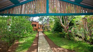 Um caminho coberto em um jardim que leva a um edifício com arquitetura tradicional.
