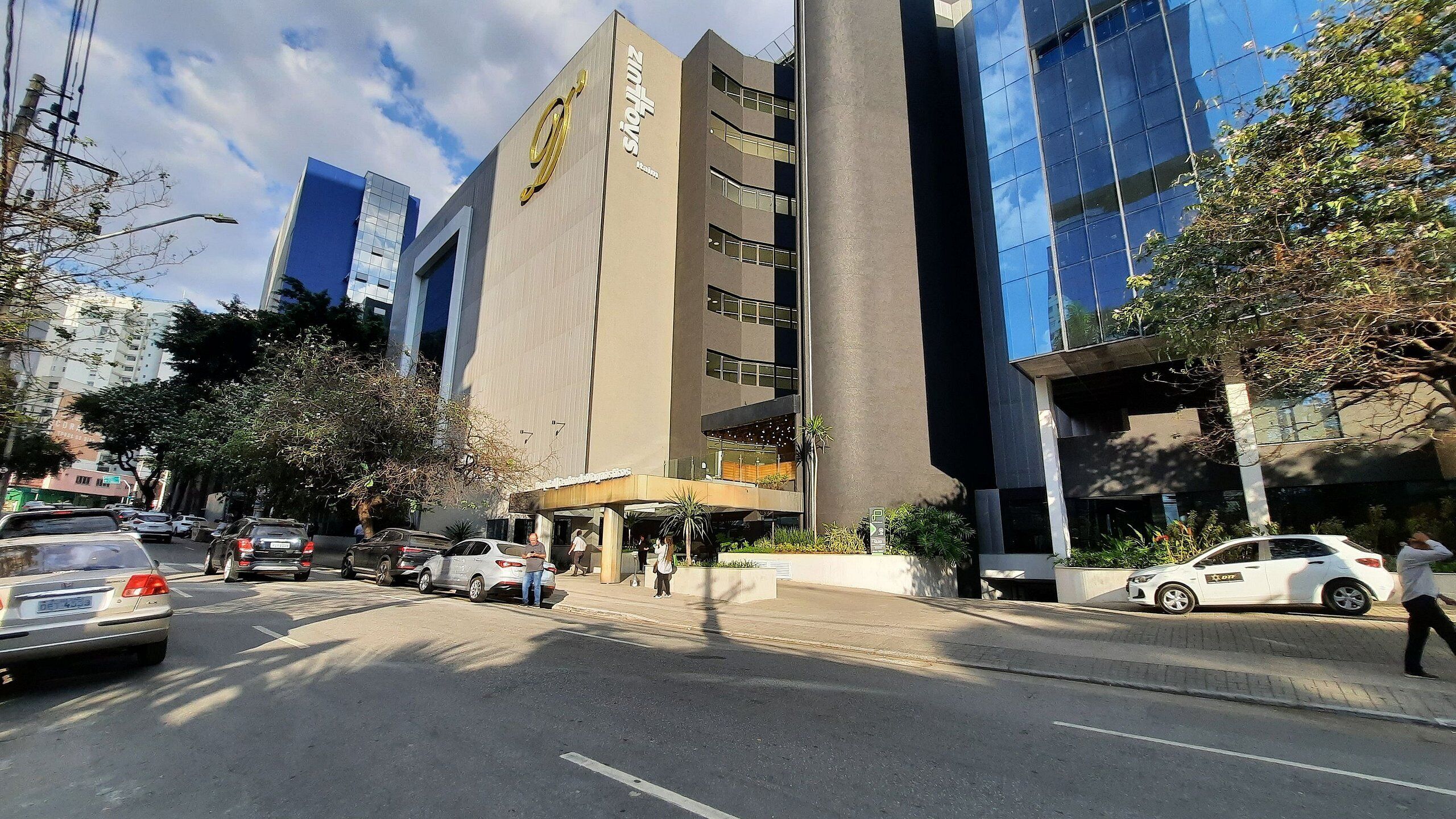 Um edifício moderno com uma placa de destaque, entrada coberta e área de estacionamento.