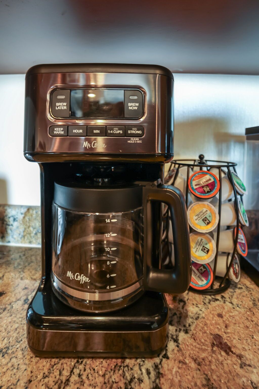 Máquina de café com painel digital, jarra de vidro transparente e nome da marca na base.
