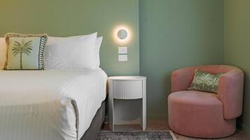 Quarto com cama, mesa de cabeceira, cadeira redonda e luminária na parede.
