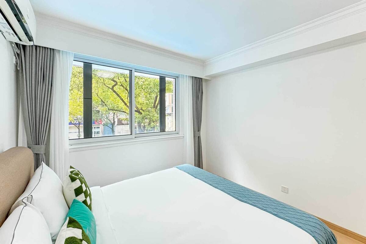 Quarto de hotel com uma cama grande, janela com cortinas e um ar condicionado.