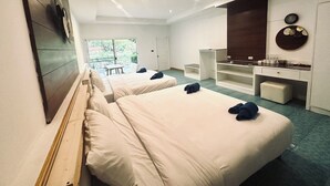Quarto de hotel moderno com duas camas, uma mesa de trabalho e vista para o exterior.