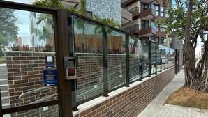 Um edifício moderno com entrada de vidro, paredes de tijolo e um caminho pavimentado.