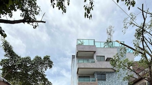 Um edifício moderno com fachada de tijolos, guarda-corpos de vidro e um caminho pavimentado.