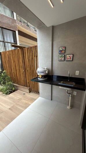 Uma cozinha moderna com bancada preta, pia e uma lata de cerveja Corona Extra. Há duas obras de arte emolduradas na parede.