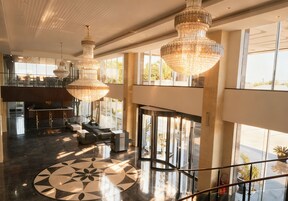 Um lobby espaçoso com um lustre moderno, um balcão de recepção e uma área de estar.