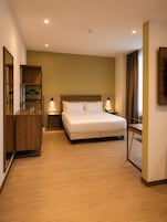 Quarto de hotel com cama, mesas de cabeceira, espelho, guarda-roupa e televisão.