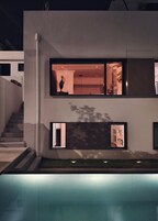 Uma casa moderna de dois andares, com escadaria visível, piscina e interior bem iluminado.