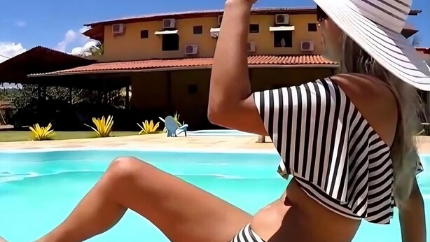 Uma pessoa sentada perto de uma piscina, com um edifício ao fundo.