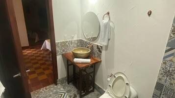 Um banheiro com vaso sanitário, pia, espelho e azulejos estampados.