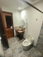 Um banheiro com vaso sanitário, pia, espelho e azulejos estampados.