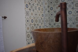 Um banheiro com uma bacia de madeira e uma torneira.