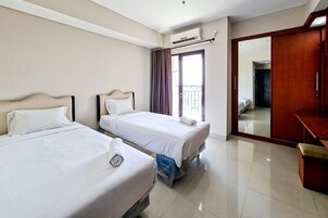Quarto de hotel com duas camas, uma escrivaninha de madeira, um espelho e porta de correr para uma varanda.