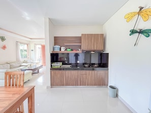 Uma cozinha moderna com armários de madeira, bancada preta e área de jantar com mesa e cadeiras de madeira.