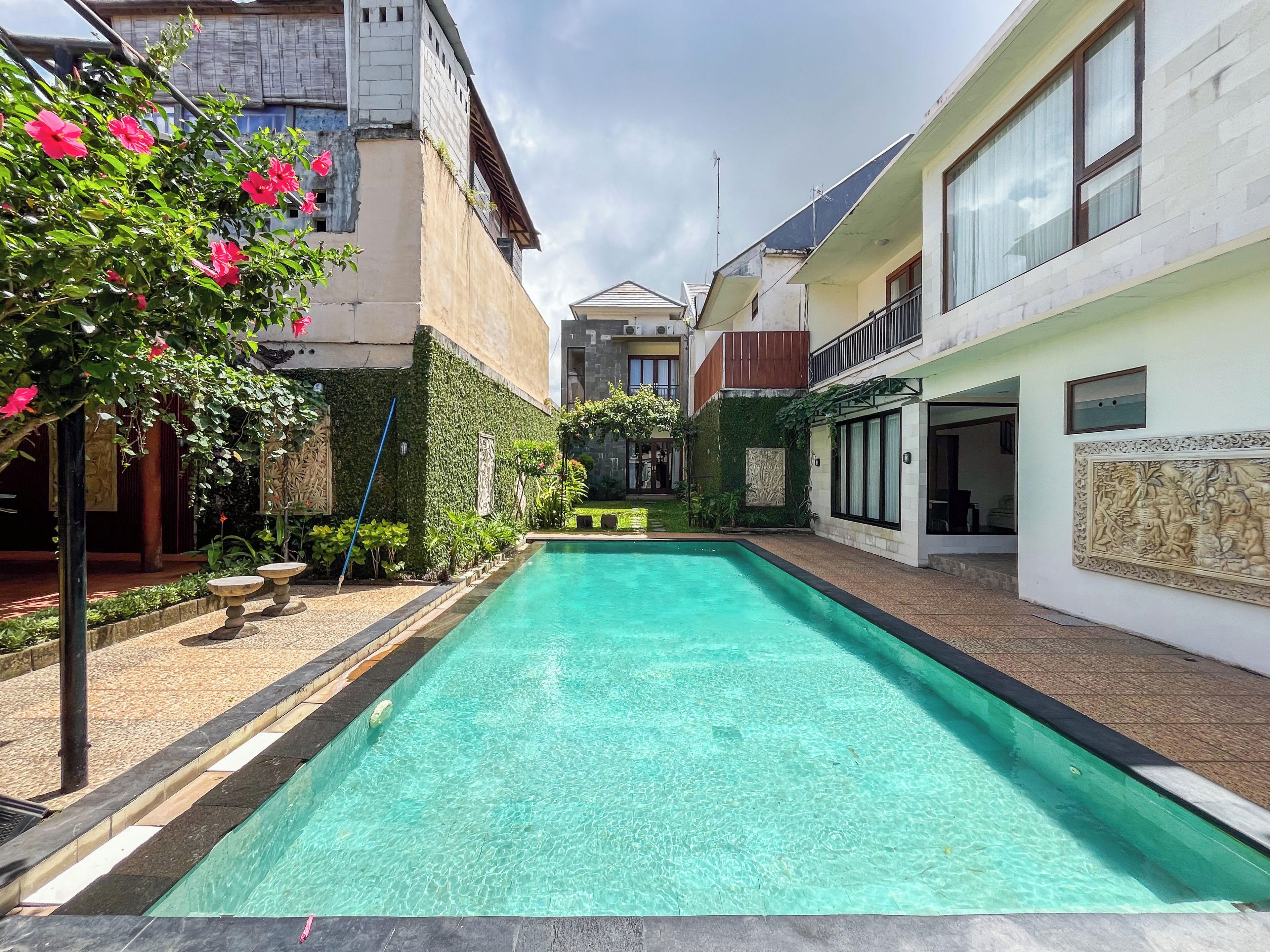 Uma piscina retangular com superfície de água azul translúcida, ladeada por uma borda de pedra.