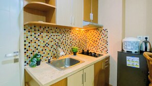Uma cozinha compacta com painel de azulejos, pia, fogão e geladeira.
