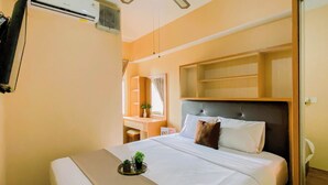 Quarto de hotel com cama, mesa de cabeceira, espelho e ventoinha no teto.