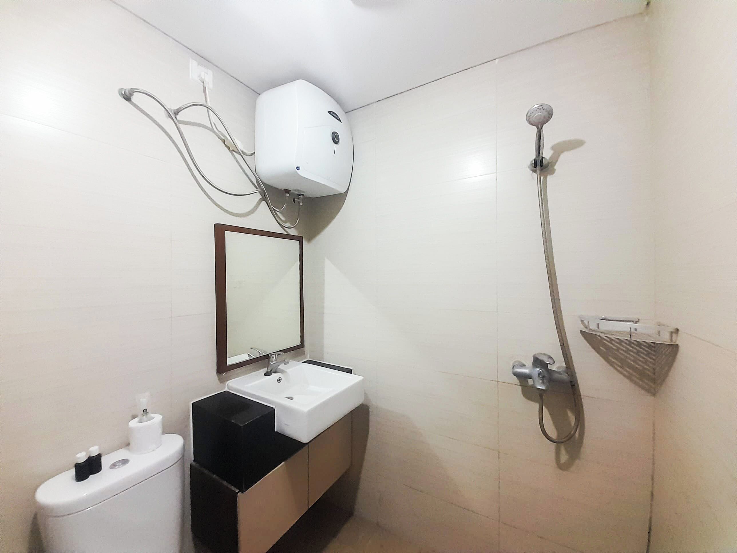 Casa de banho com lavatório branco, espelho e chuveiro com duche manual.