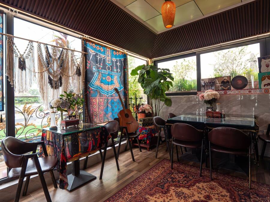 Uma sala de jantar com mesa de vidro, cadeiras e uma planta grande.