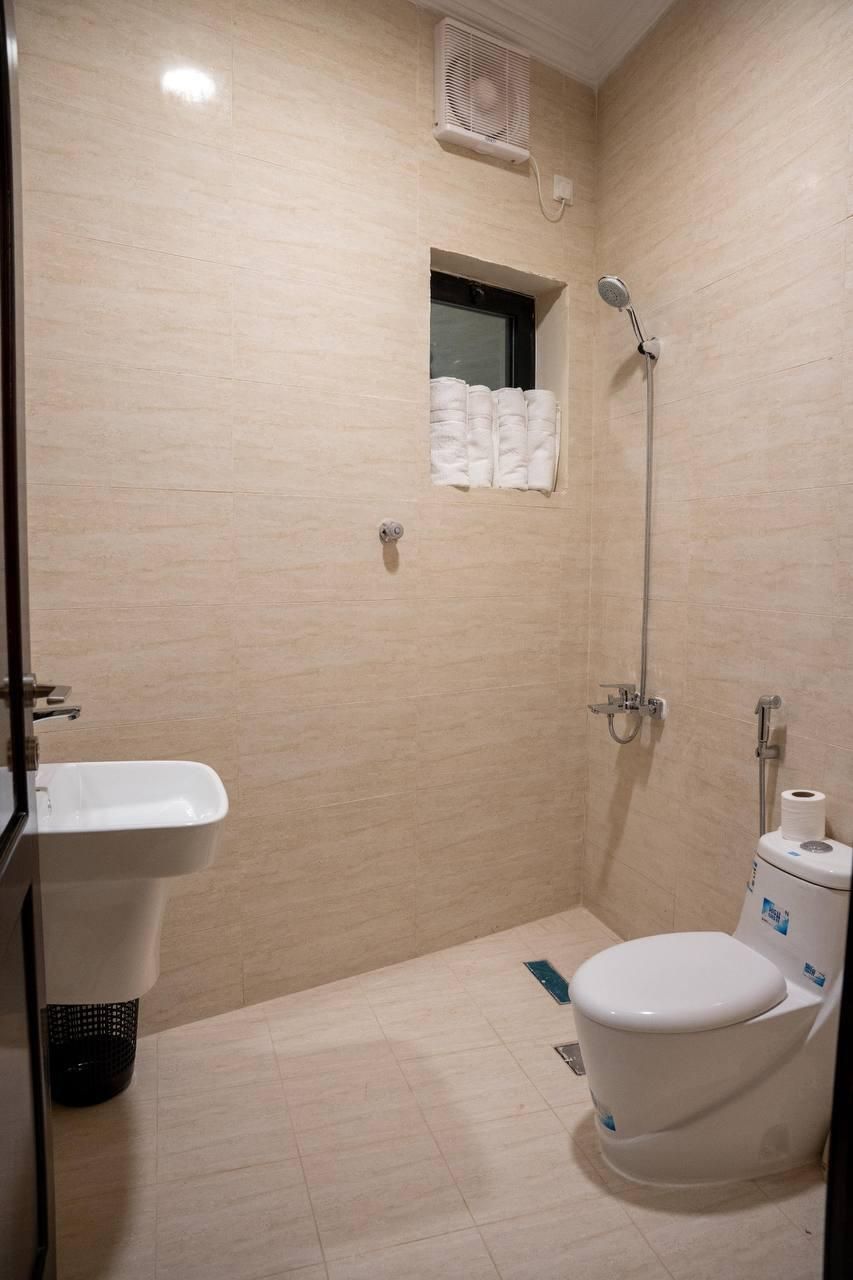 Um banheiro pequeno com azulejos, vaso sanitário, pia e chuveiro.