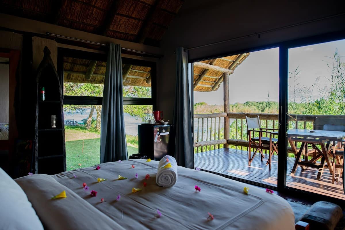 Quarto com cama, cafeteira e vista para um terraço.