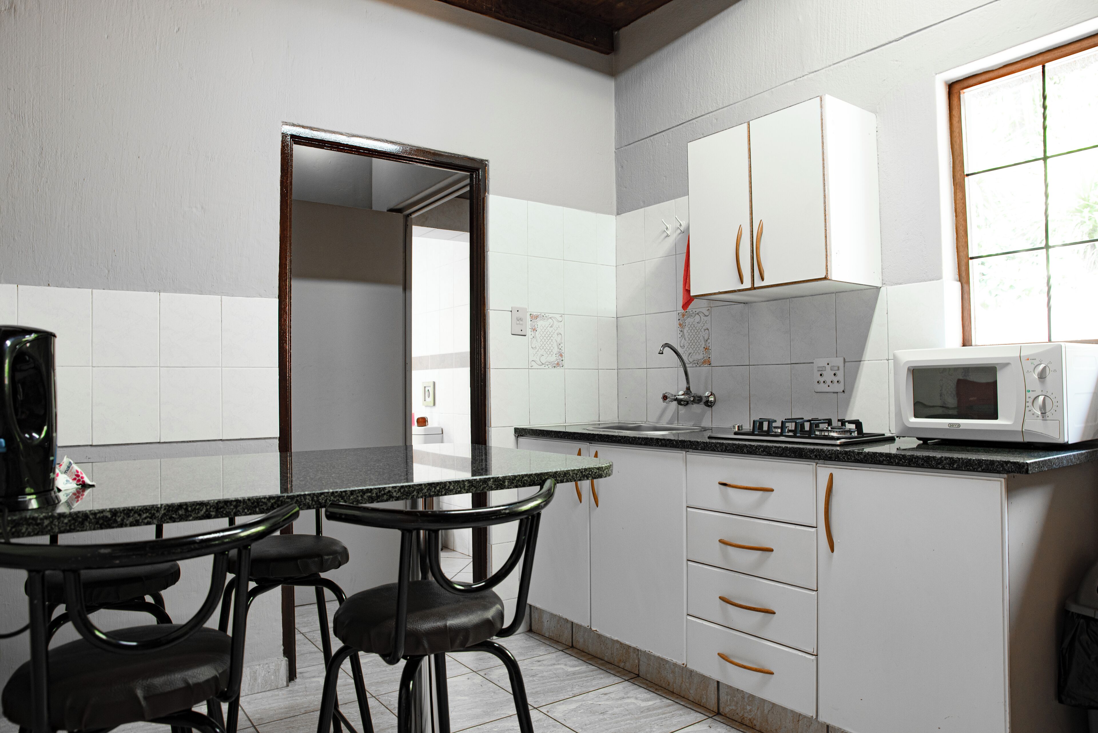Cozinha com armários brancos, bancada preta e micro-ondas.